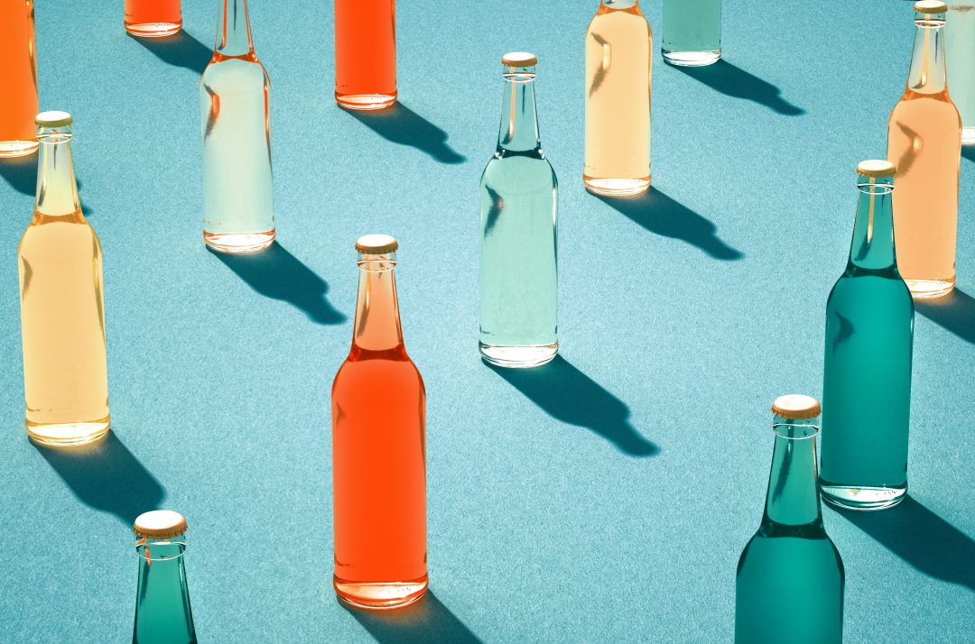 Various color glass bottles with shadows on blue surface. | Customer ...